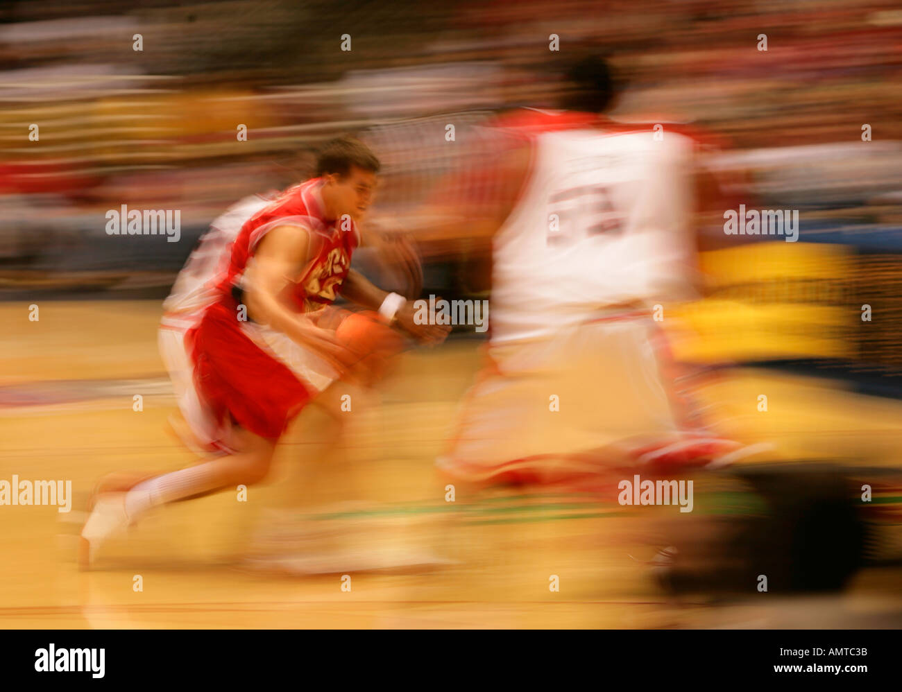 A slow shutter speed shot of a basketball player dribbling down court ...