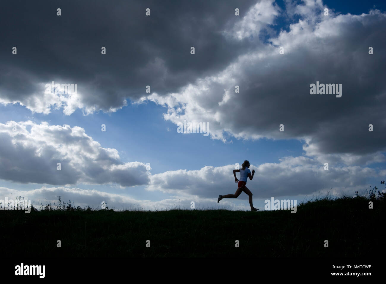 Running woman as a silhouette in front of a sky with dark clouds Stock ...