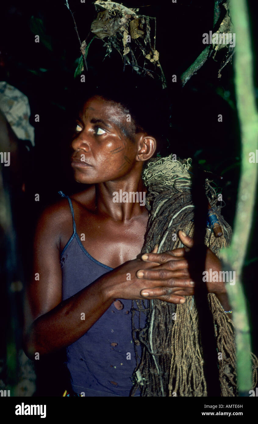 Portrait of pygmy woman in forest with a hunting net slung over her ...