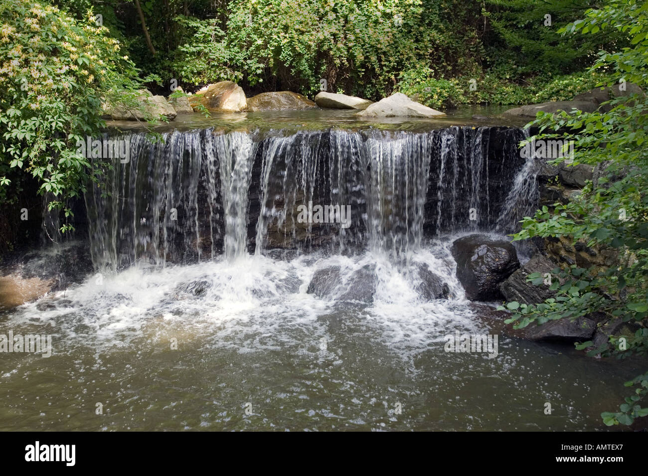 Sun hitting most of a small waterfall Stock Photo - Alamy