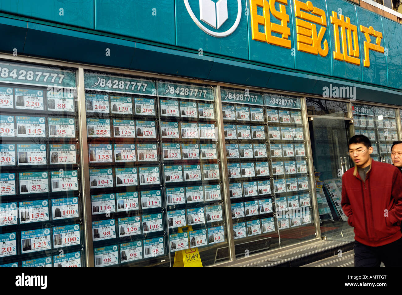 A man walks past an estate agent's window where coloured cards ...