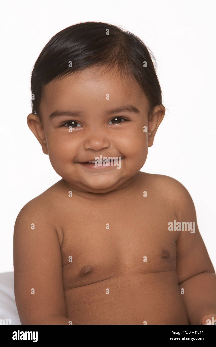 A brunette baby sits against a white background and smiles Stock Photo ...