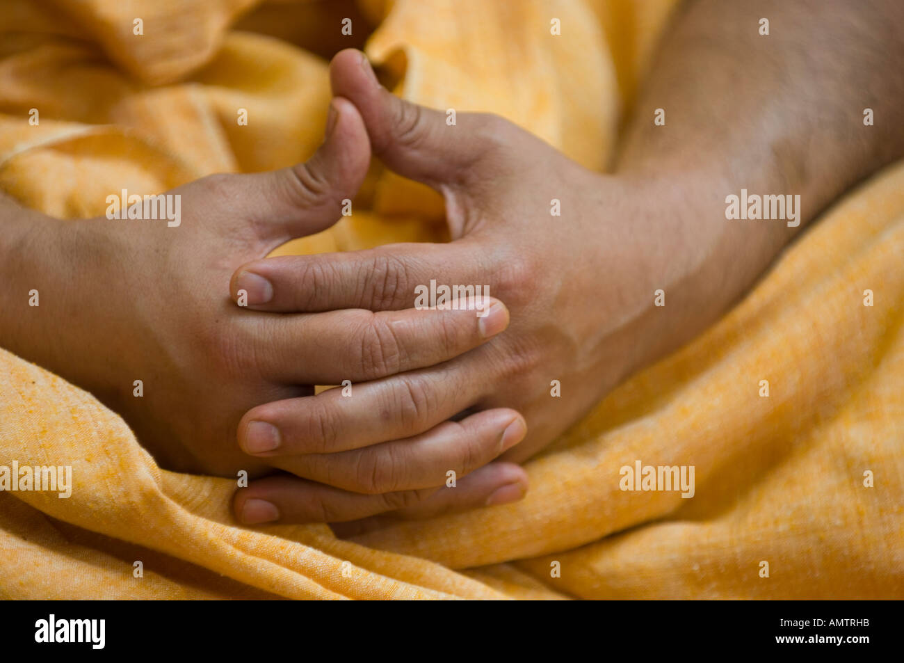 Hindu monk's hands on orange robes Stock Photo - Alamy