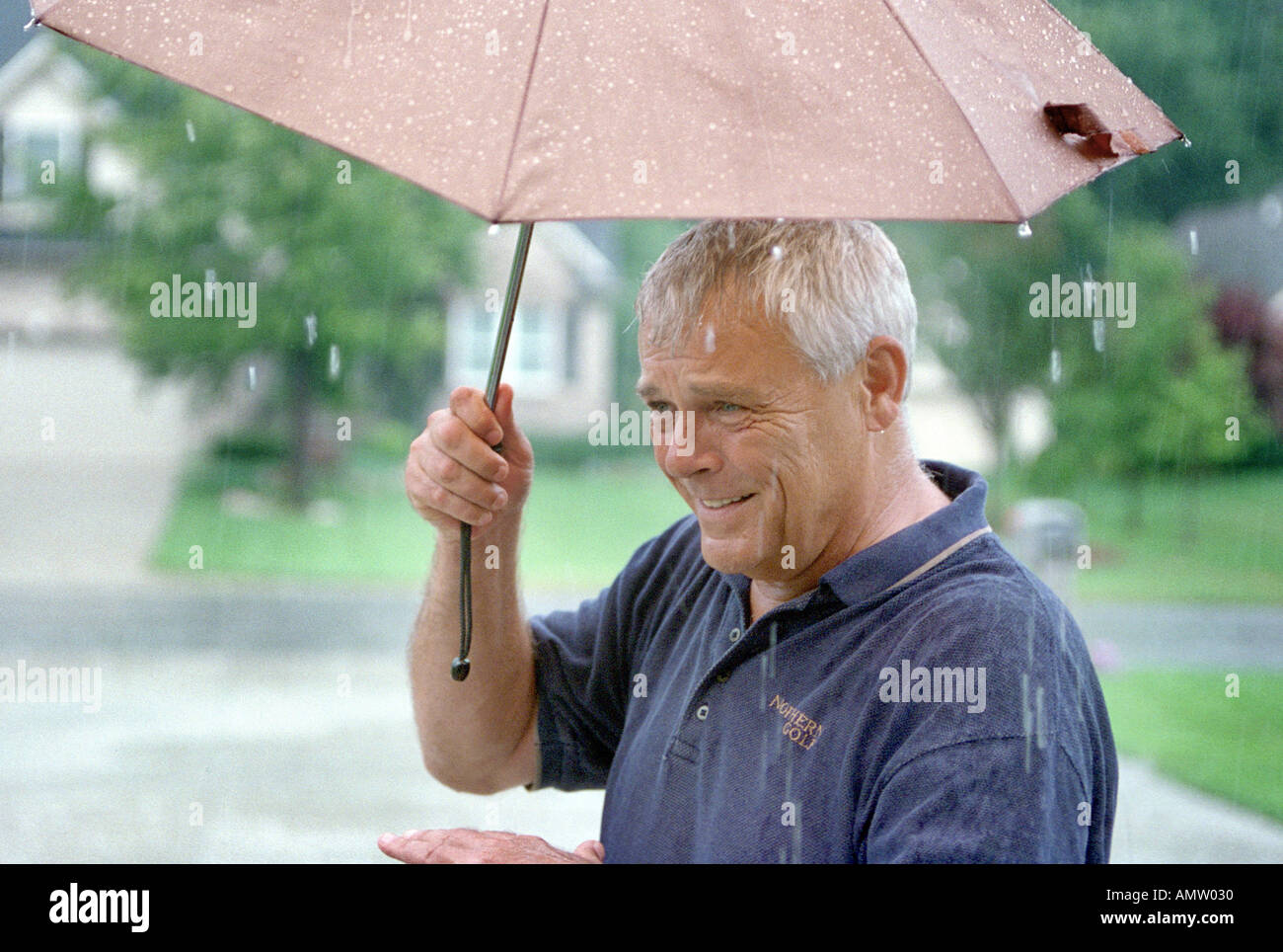 Adult attempts to shield self from rain with an umbrella Stock Photo ...