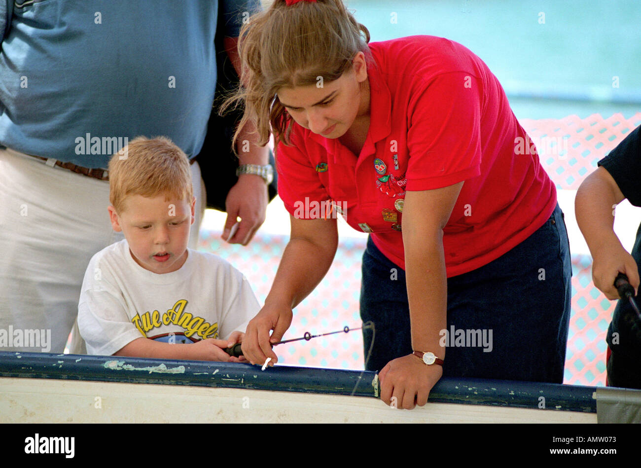 Female helps boy to try to catch a fish in a tank MR Stock Photo - Alamy