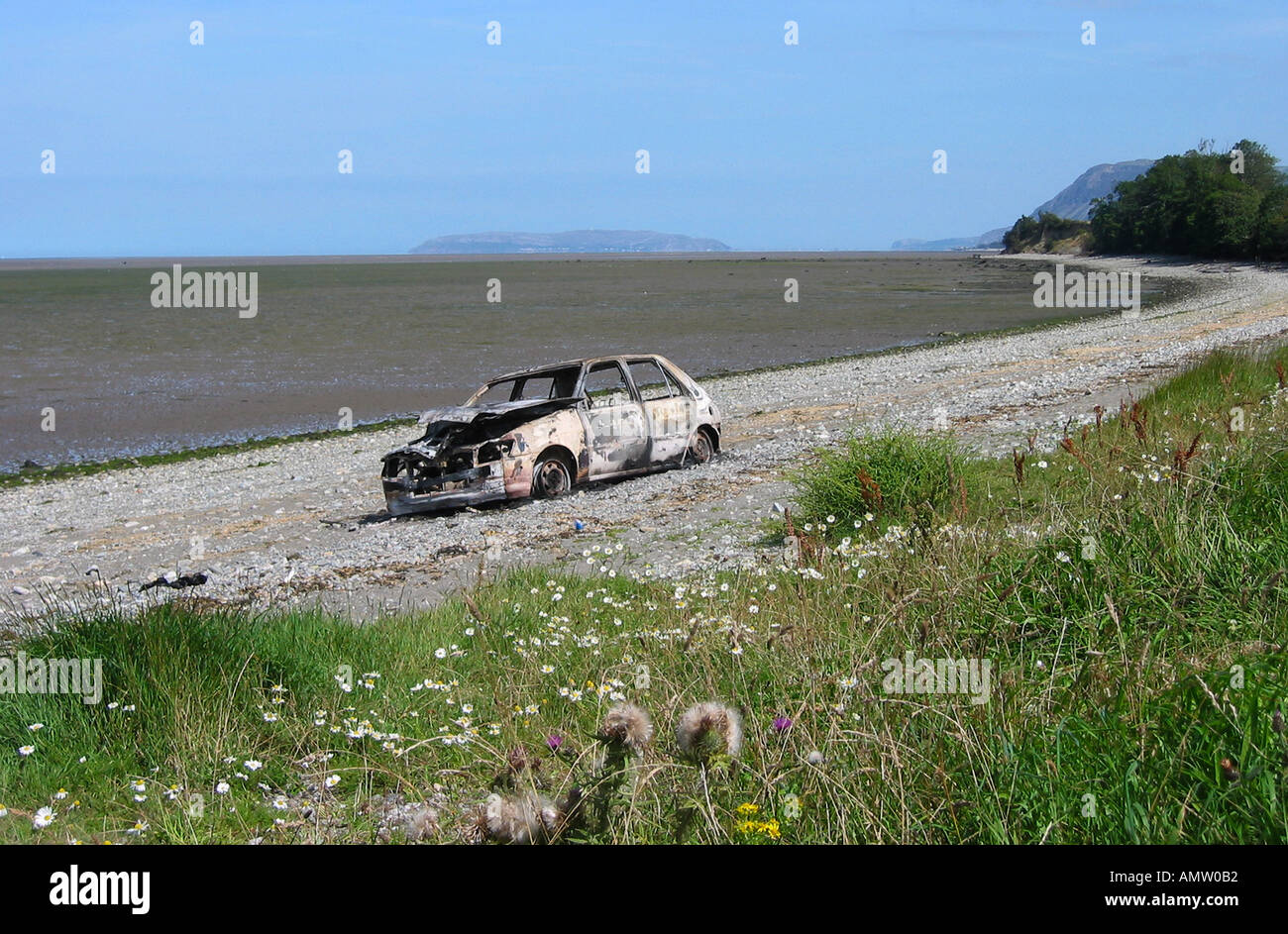 Burnt out car abandoned on welsh beach Stock Photo - Alamy