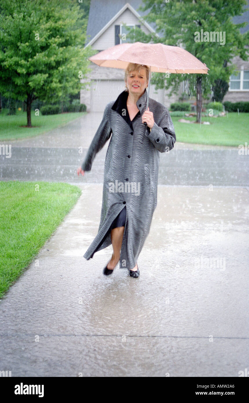 Adult attempts to shield self from rain with an umbrella Stock Photo ...