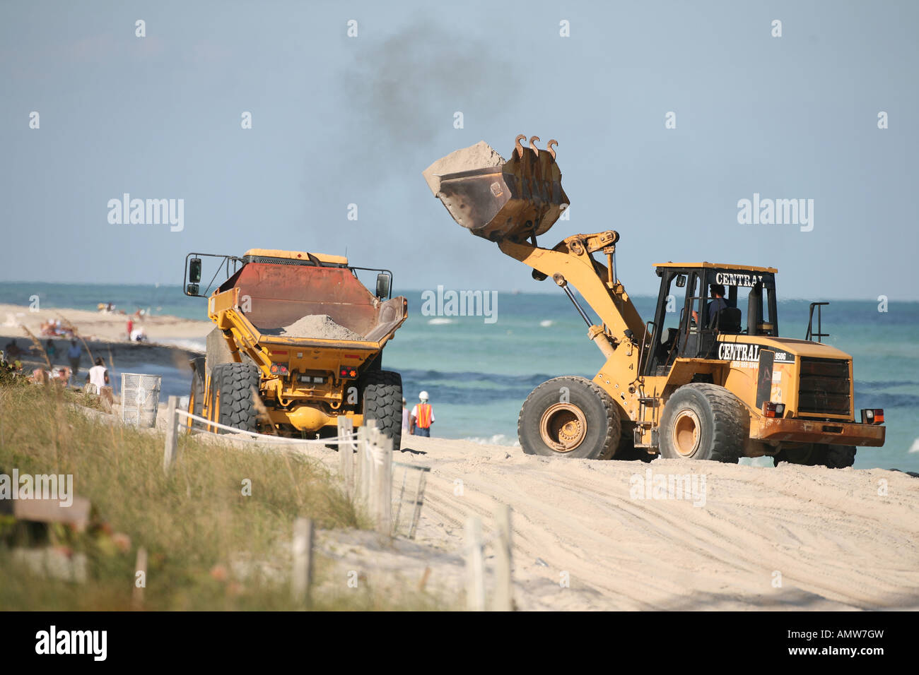 Workers move sand on the beach in Miami with heavy lifting equipment ...