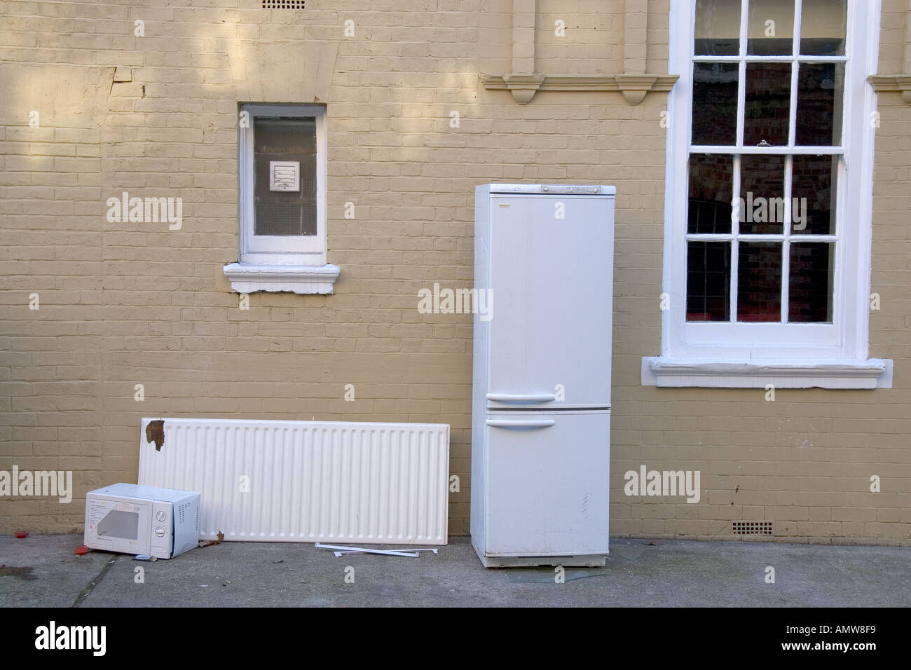 Refrigerator radiator and microwave oven discarded on sidewalk pavement ...