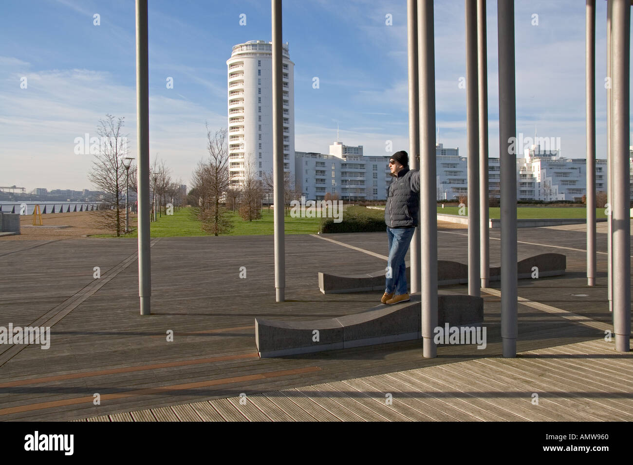Man standing on decking looking into bright sunshine with apartment ...