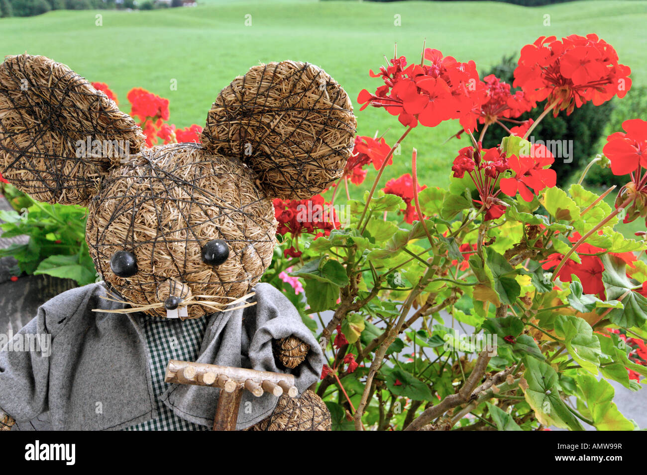 Straw rabbit with rake by red flowers - Traditional straw rabbit with ...