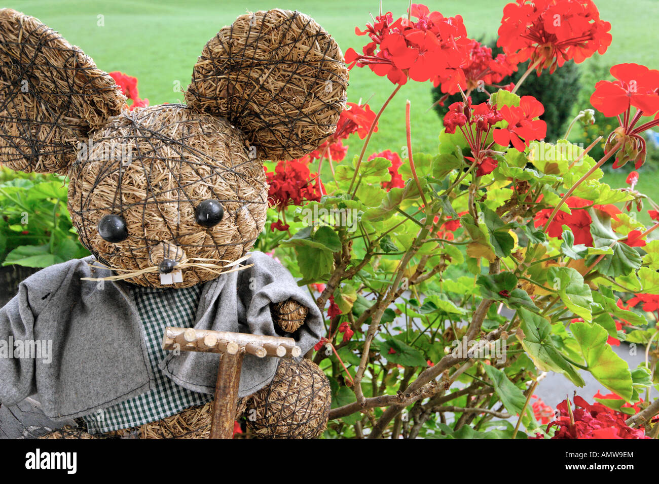 Straw rabbit with rake by red flowers - Traditional straw rabbit with ...