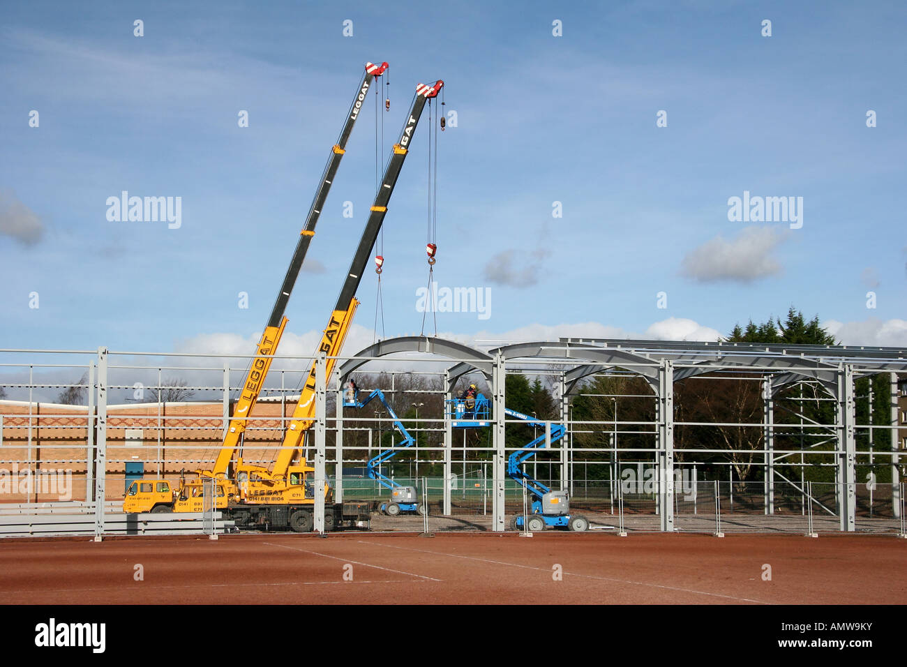 Cranes lifting steel beams on construction site Stock Photo - Alamy