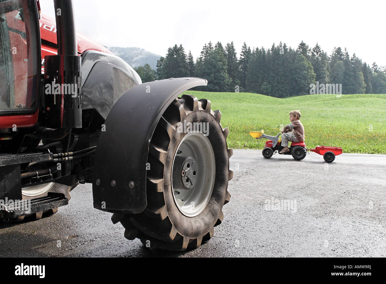 Large tractor and child on toy tractor - Young child pedaling toy ...
