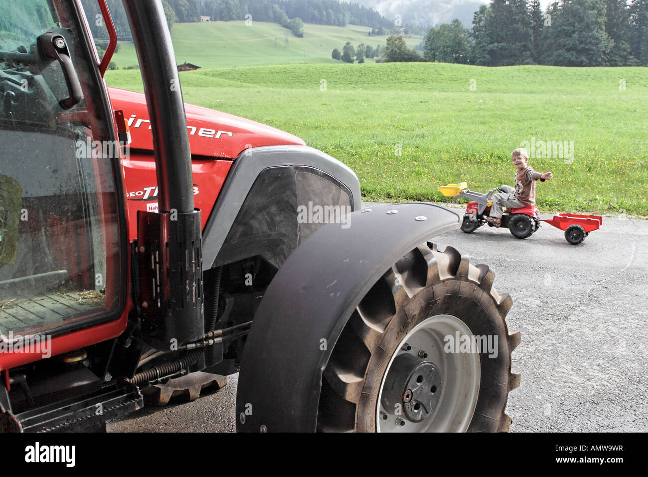 Large tractor and child on toy tractor - Young child pedaling toy ...