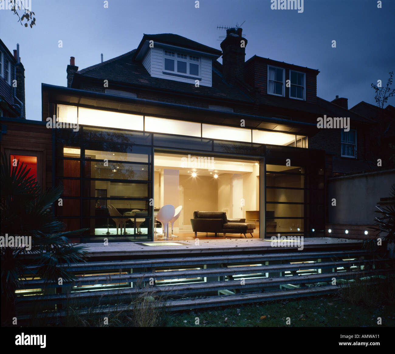 Modern House Extension, W12. Exterior at night with patio doors open ...