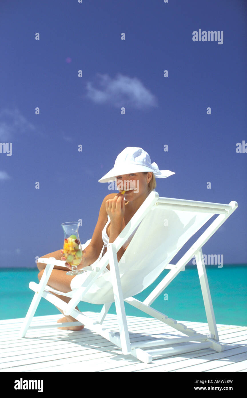 USA, Hawaiian Islands. Woman wearing all white sitting on dock eating ...