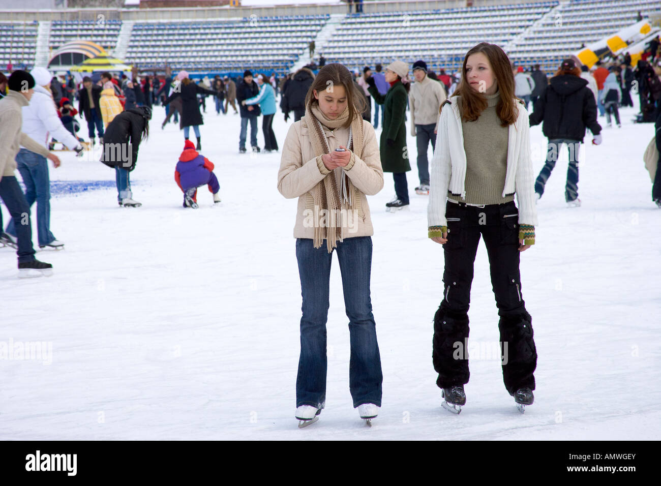 Two girls skating at Medeo skating rink one with mobile phone amongst ...