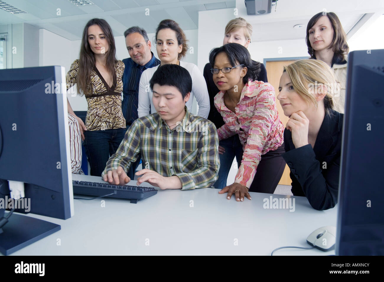 Young men and young women looking at computer in classroom Stock Photo ...