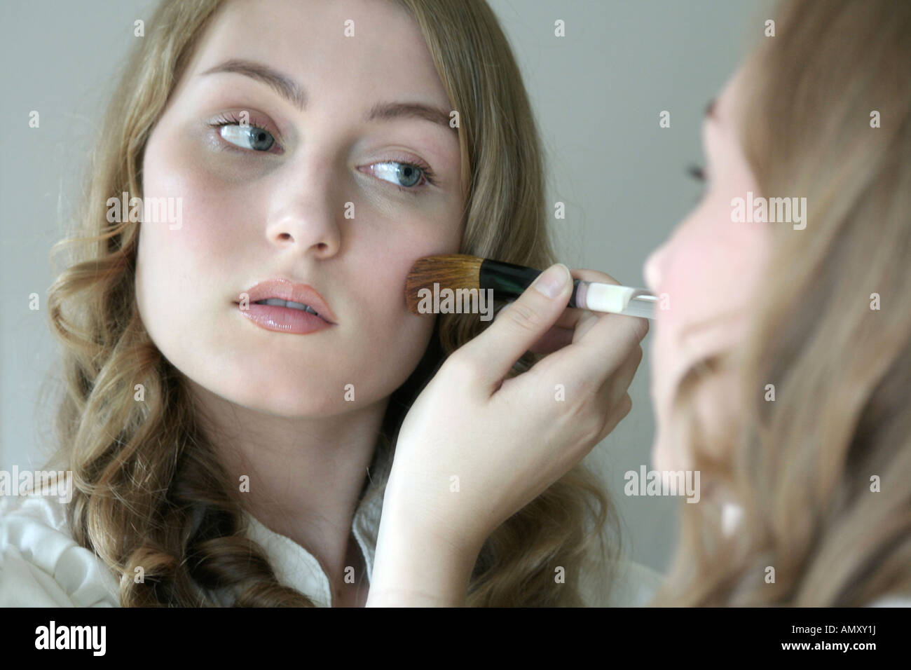 Reflection of young woman applying blusher with a brush in mirror Stock ...