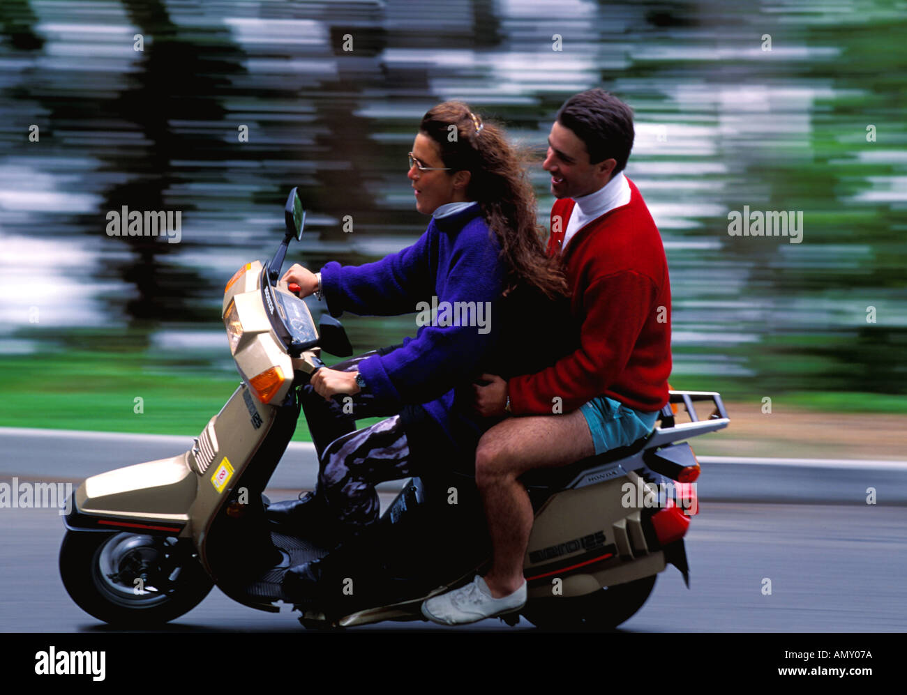 A young couple lean into a turn at high speed on a motor scooter Stock ...