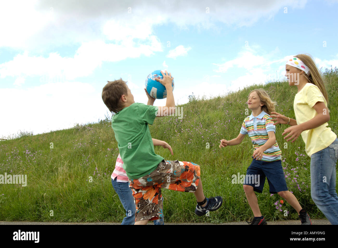 four children playing with ball in field Stock Photo - Alamy