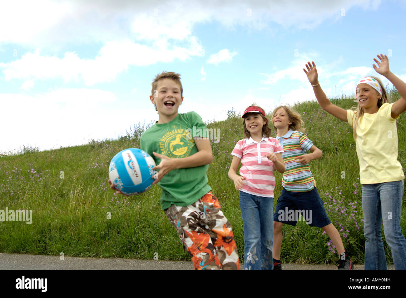 four children playing with ball in field Stock Photo - Alamy