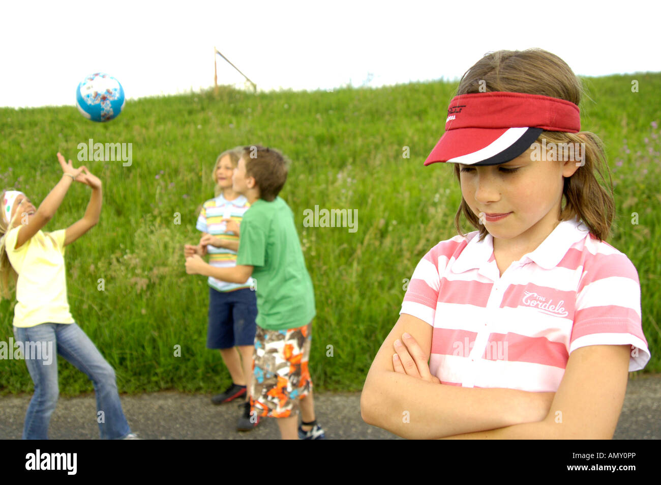 Close-up of girl looking sad with her friends playing with ball in ...
