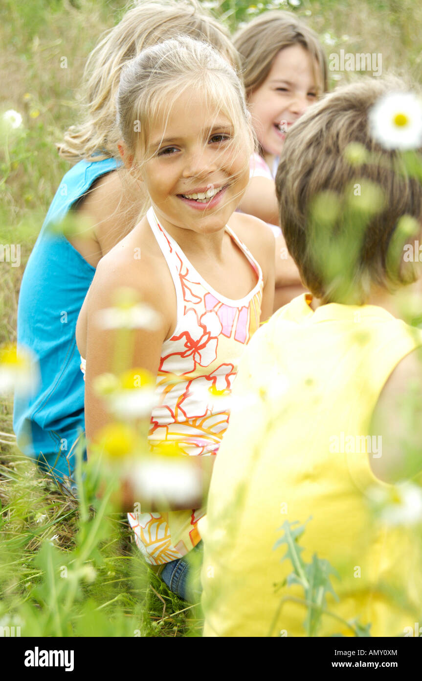 Side profile of four children sitting in field Stock Photo - Alamy