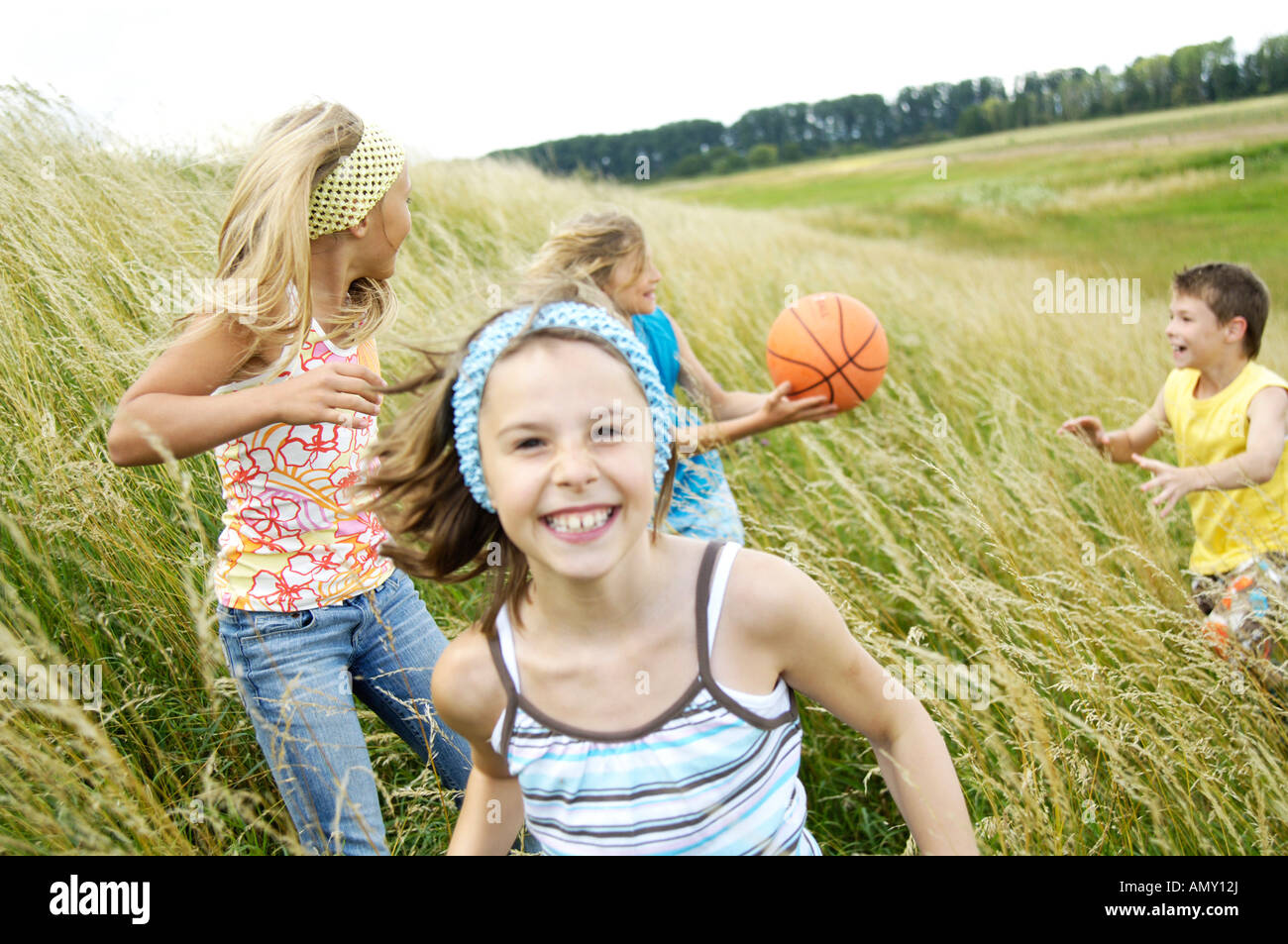 four children playing in field Stock Photo - Alamy