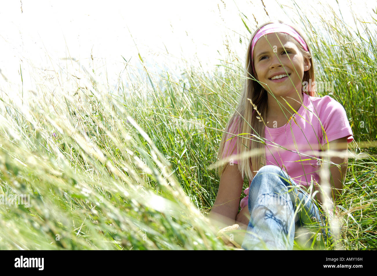 Girl sitting in field and smiling Stock Photo - Alamy