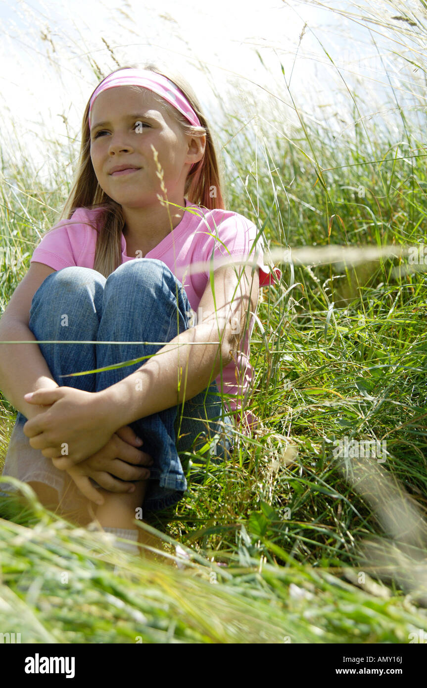 Girl sitting in field and thinking Stock Photo - Alamy