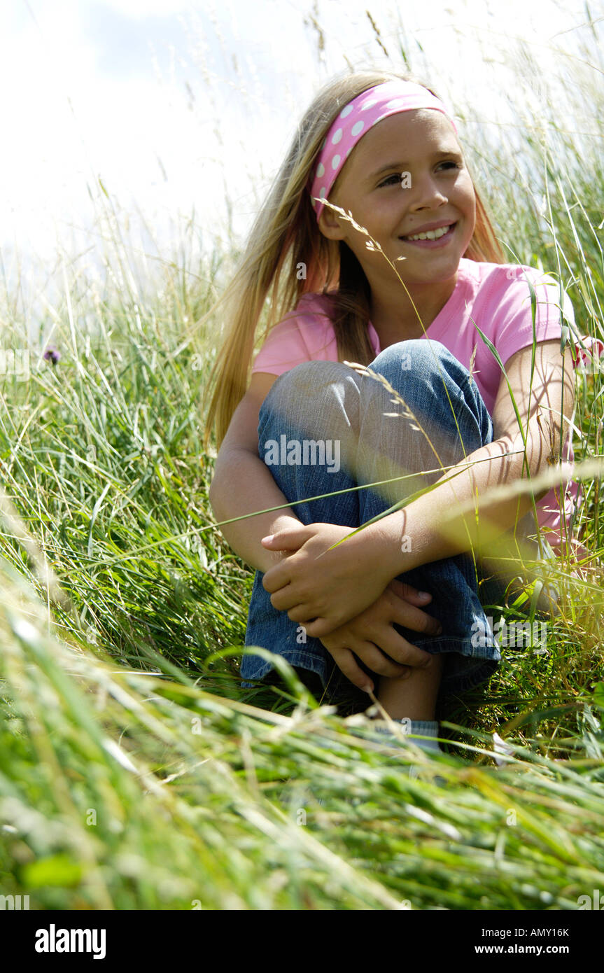 Girl sitting in field and smiling Stock Photo - Alamy