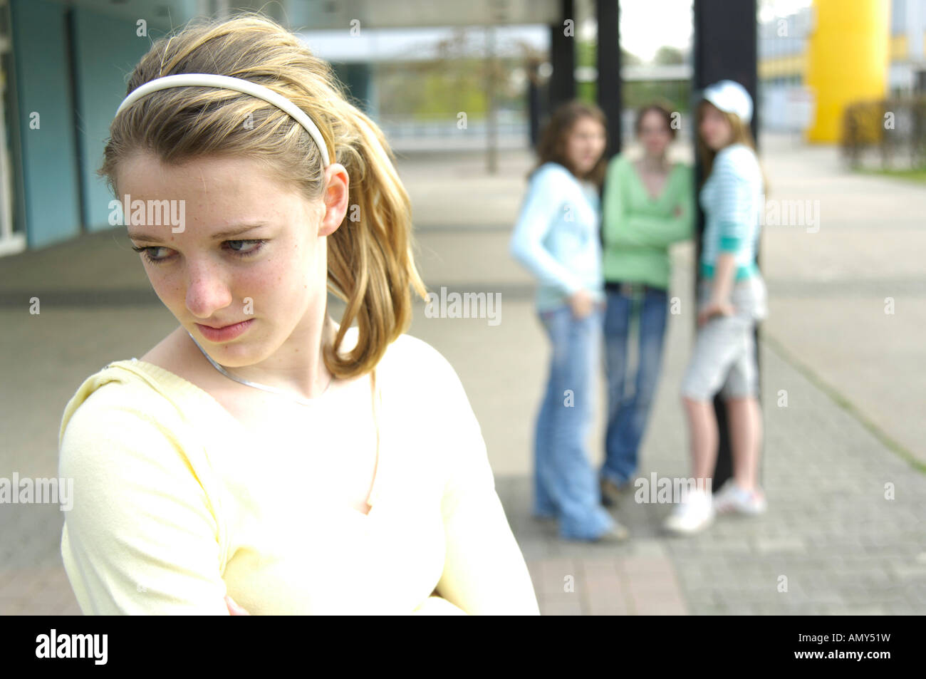 Close-up of teenage girl looking sad with her friends standing in ...