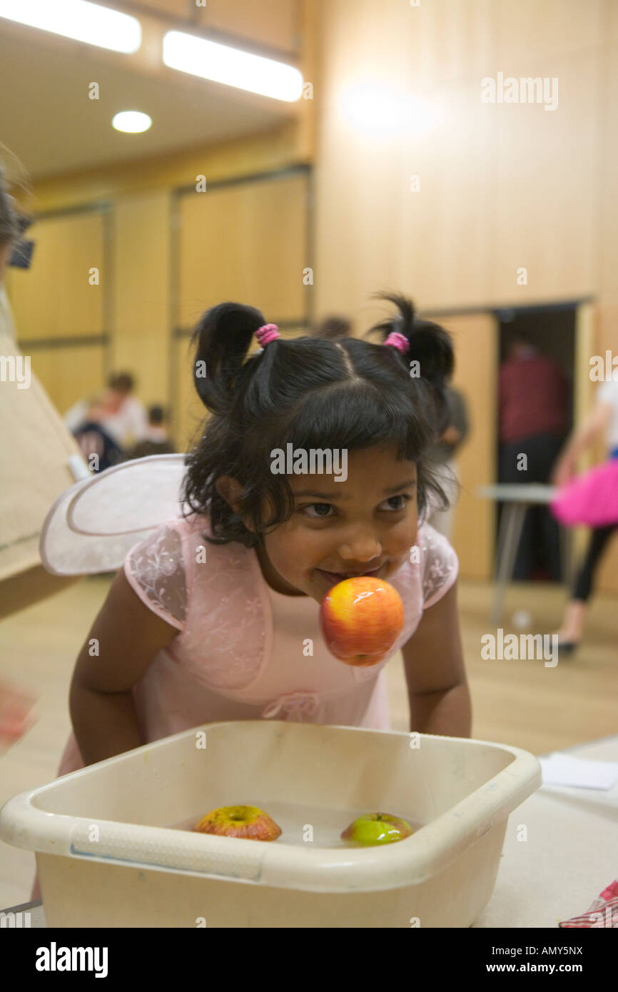 Young girl dressed as angel enjoys bobbing apples at alternative ...