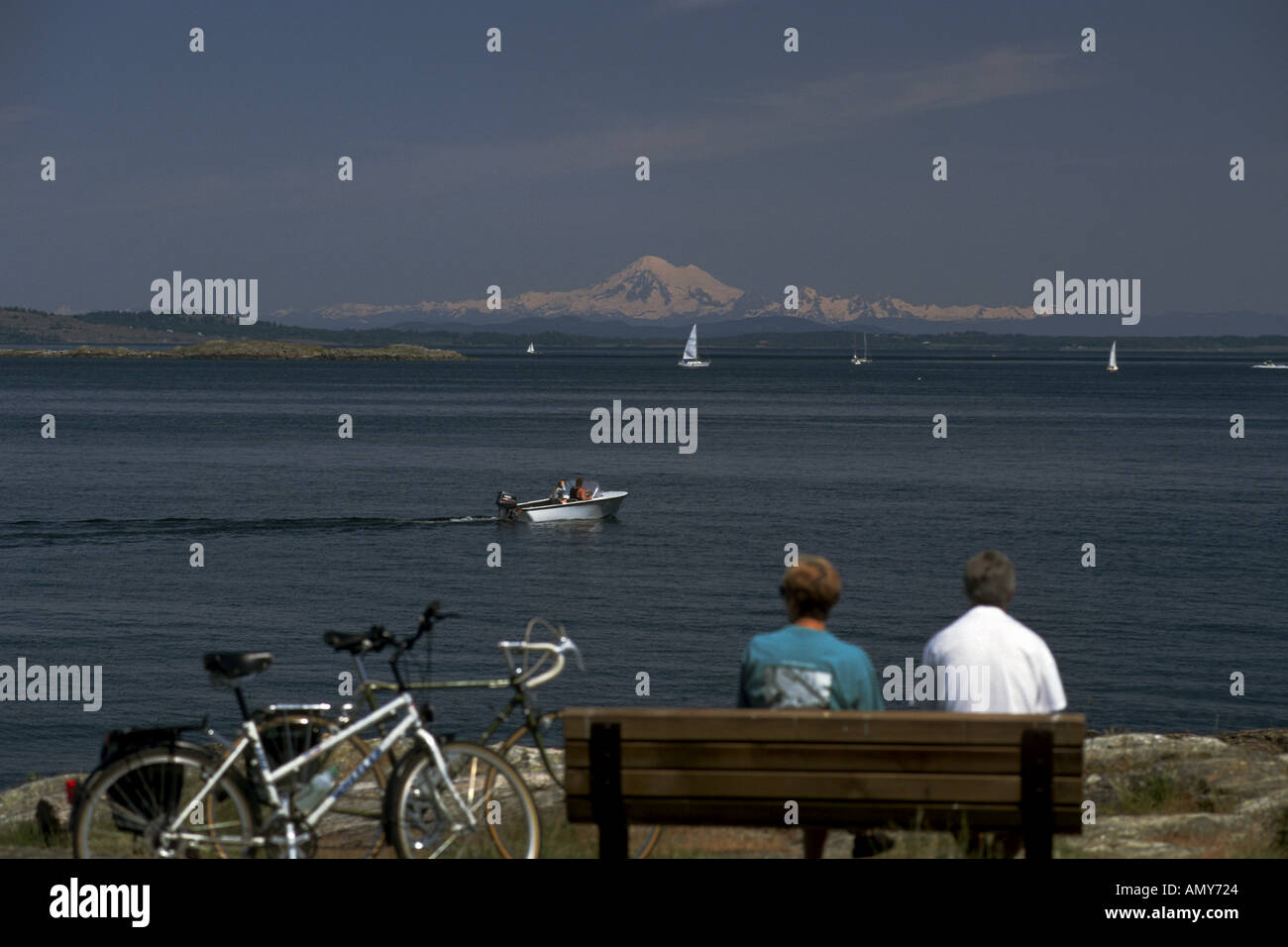 Two people resting on bench Haro Strait shoreline Mount Baker Victoria ...