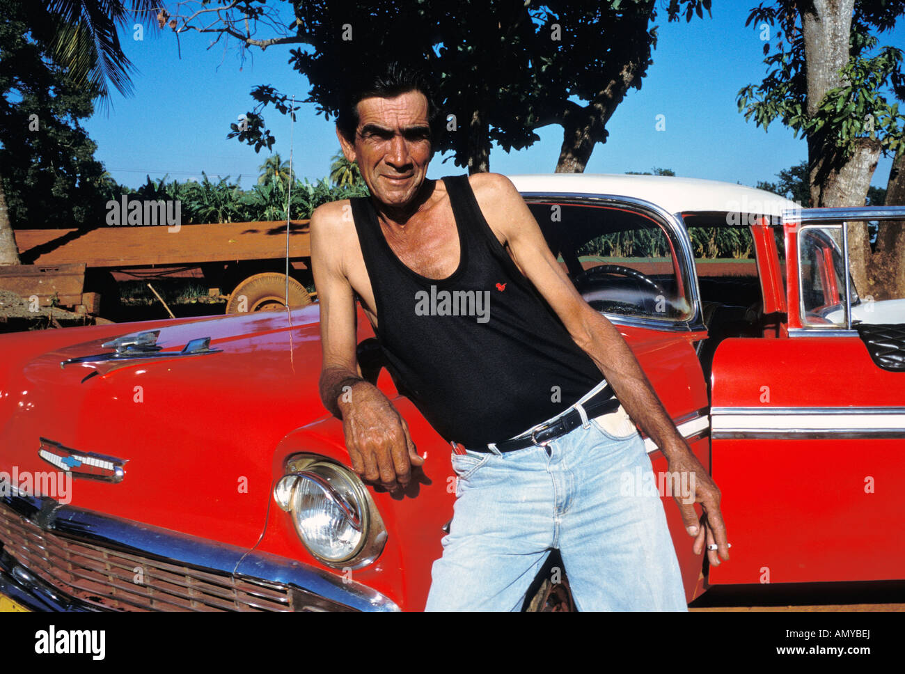 Farmer posing with his vintage red Chevrolet on his farm in Güira de ...