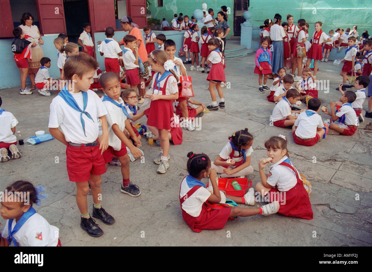 Primary school children eating packed lunches in playground during ...