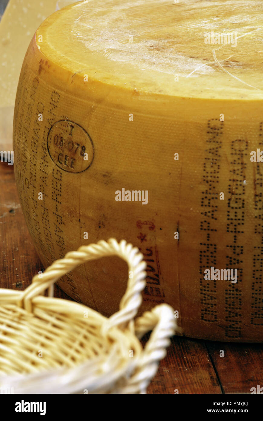 A stack of wicker baskets and a round of Parmesan cheese on a table ...