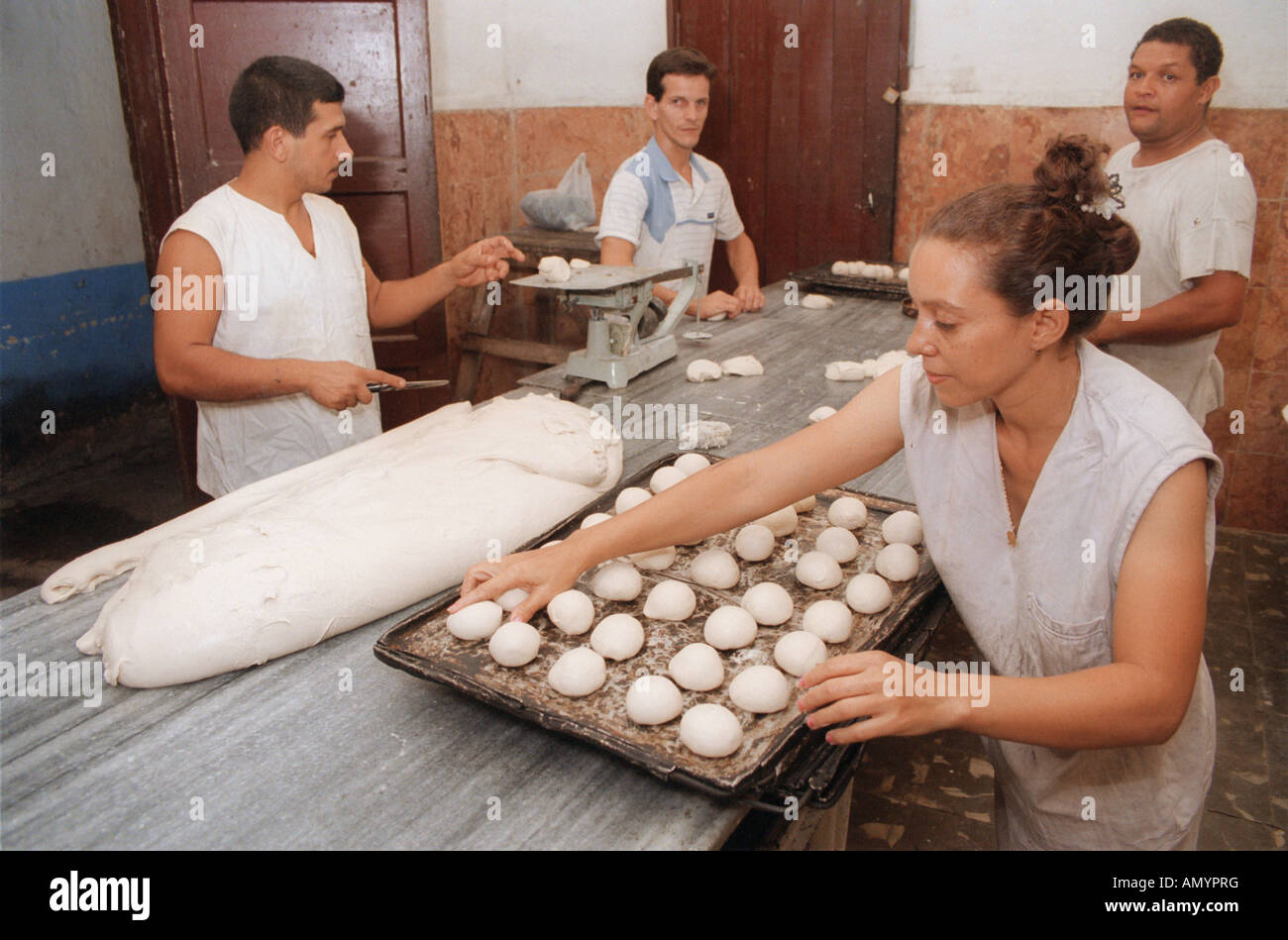 Bakers rolling out dough and shaping bread rolls in bakery in Havana ...