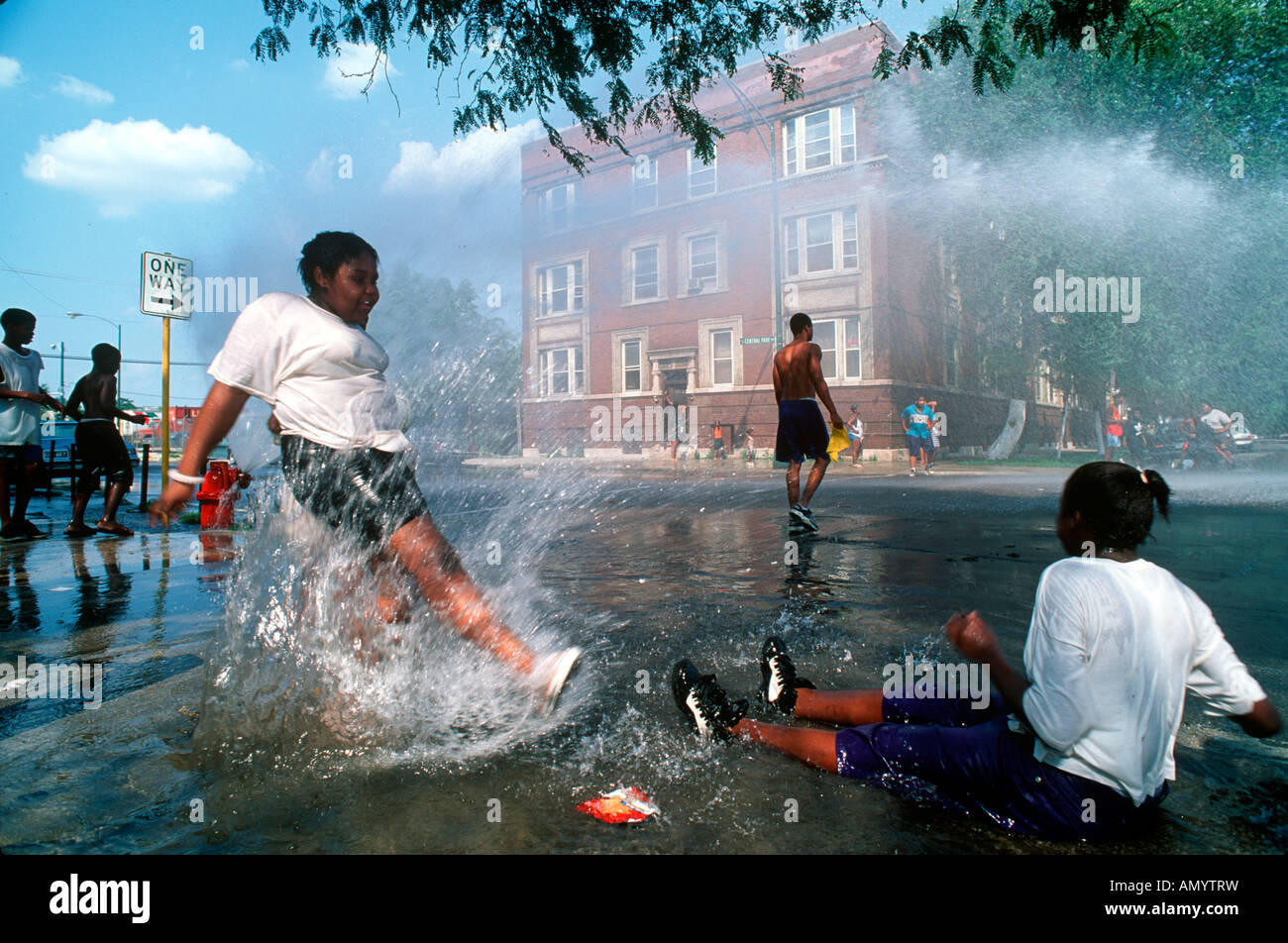 USA, Illinois, Chicago, kids cool off in opened fire hydrants during a ...