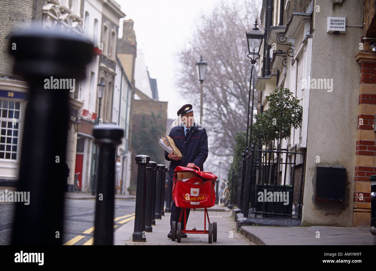 ROYAL MAIL POSTMAN PUSHES TROLLEY DELIVERING ROYAL MAIL,CHELSEA Stock ...
