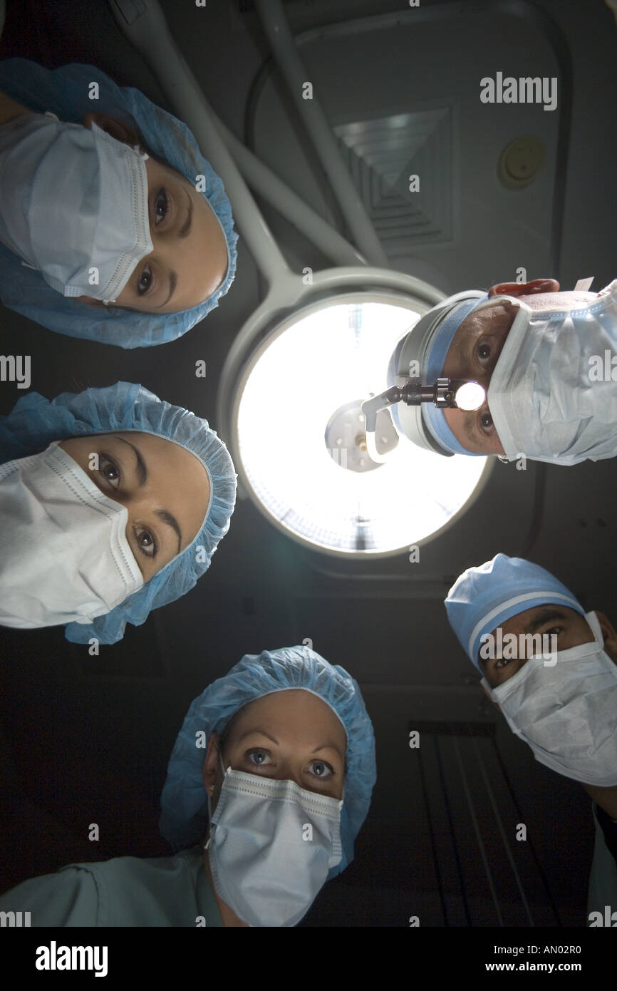 Low angle view of five surgeons standing over an operating table Stock ...