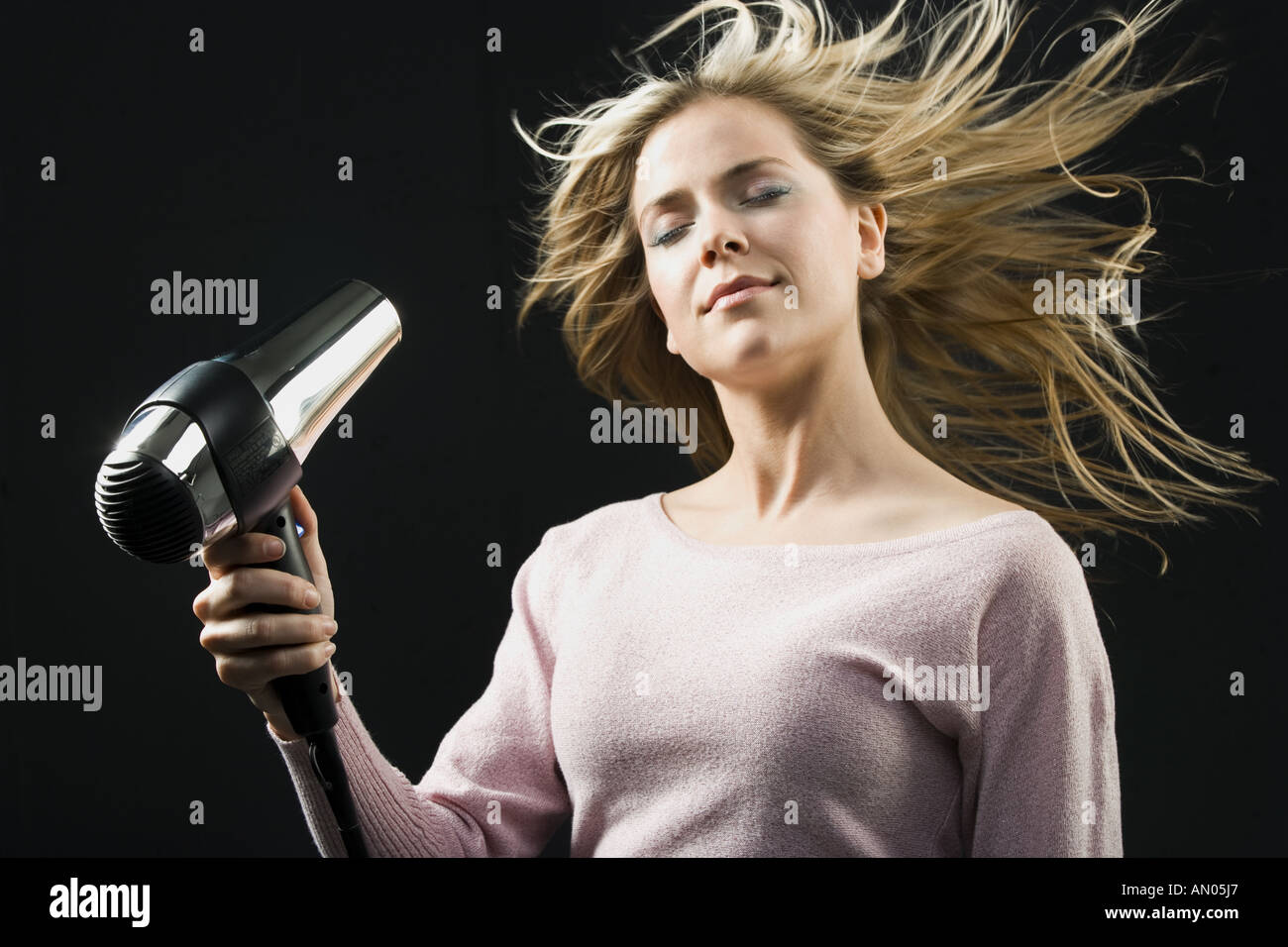 Close up of a young woman blow drying her hair Stock Photo - Alamy