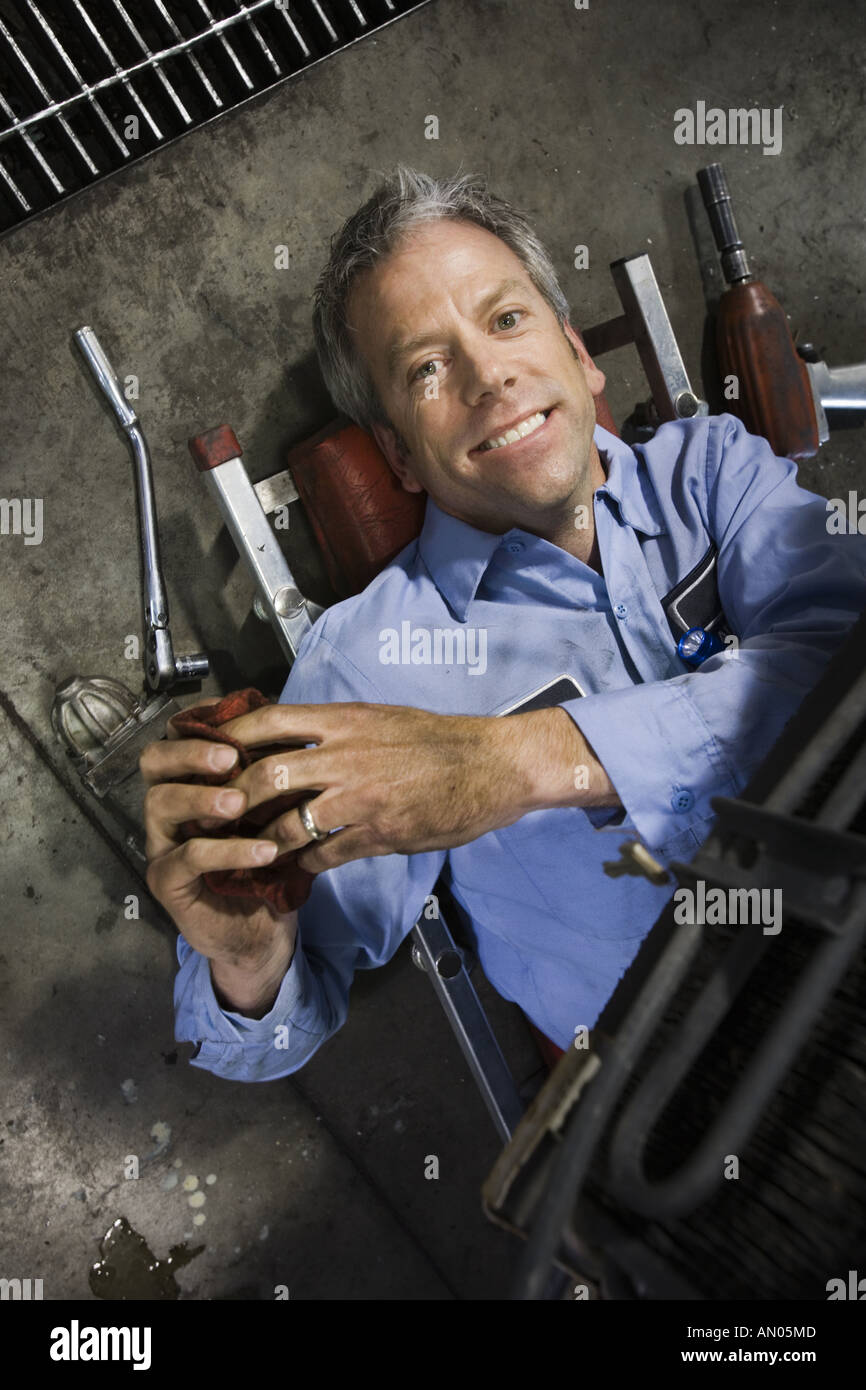 Portrait of a mechanic lying under a car and smiling Stock Photo - Alamy