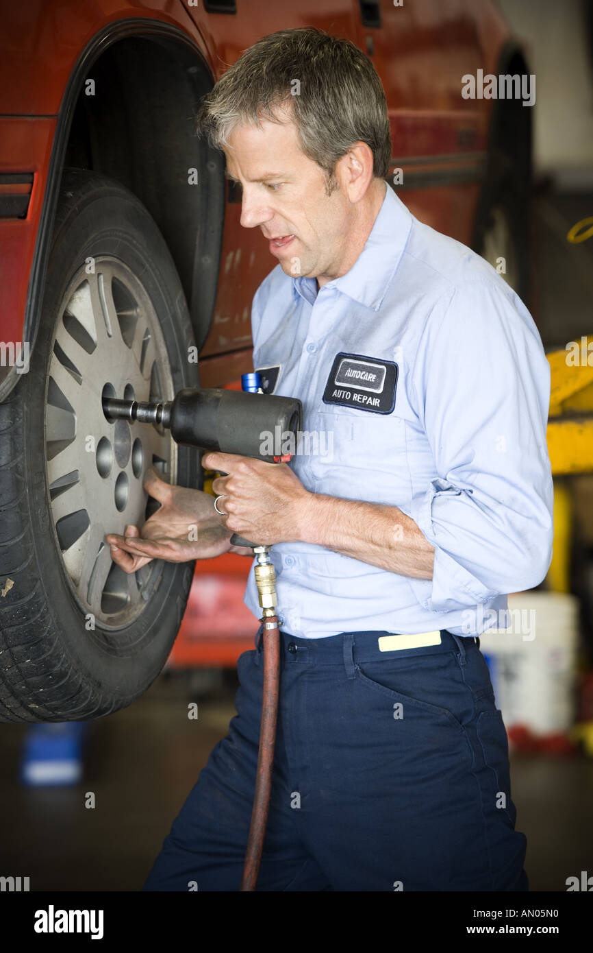 Profile of a mechanic fixing tire with a power tool Stock Photo - Alamy