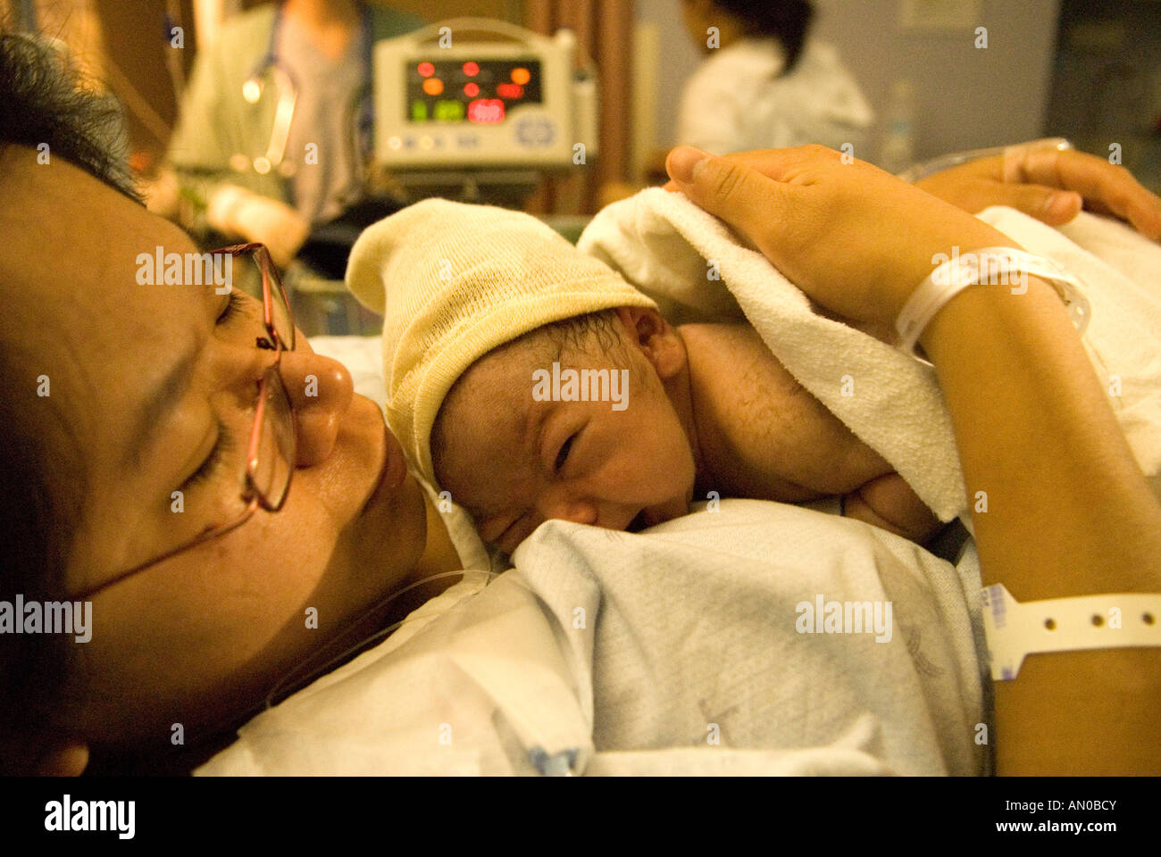 Woman in hospital holding her new born child shortly after having given ...