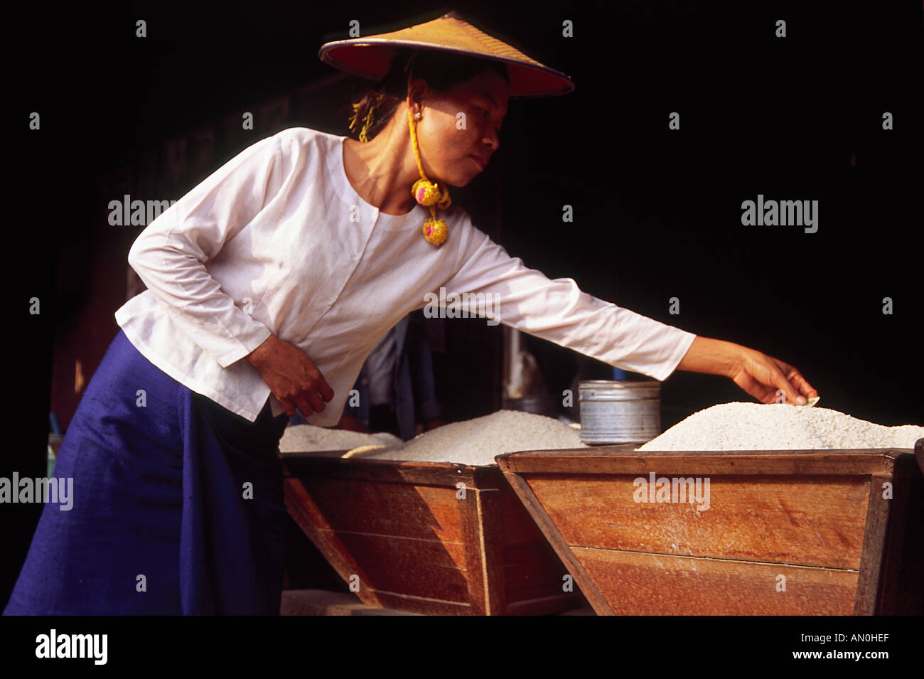 A native Burmese woman examining rice at the market in Burma Myanmar ...