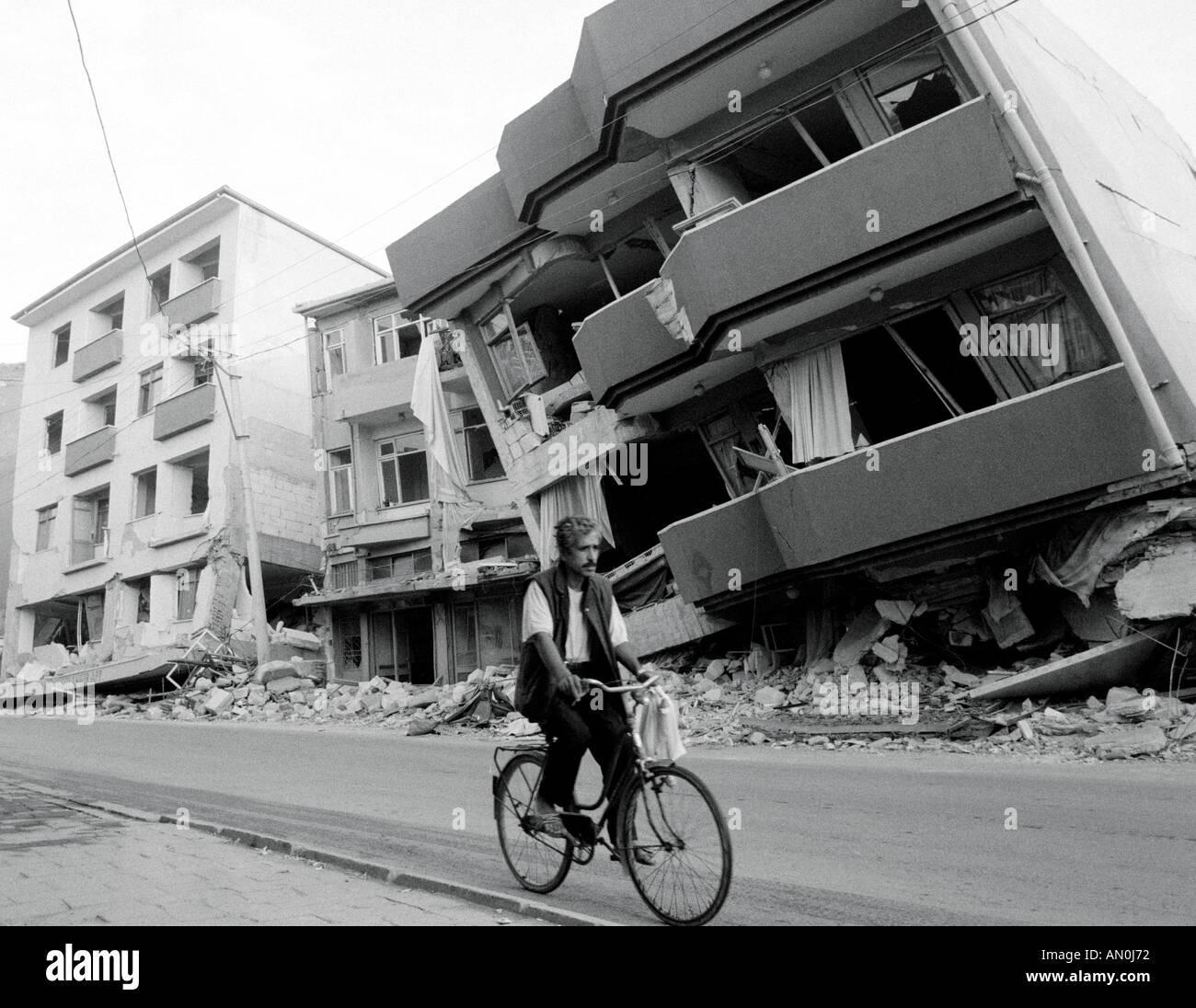Man cycling past the remains of collapsed buildings soon after the 1999 ...