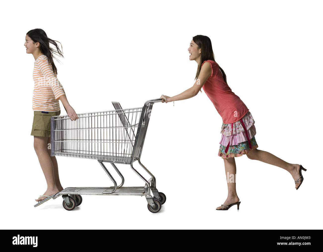 Profile of a young woman pushing a teenage girl in a shopping cart ...